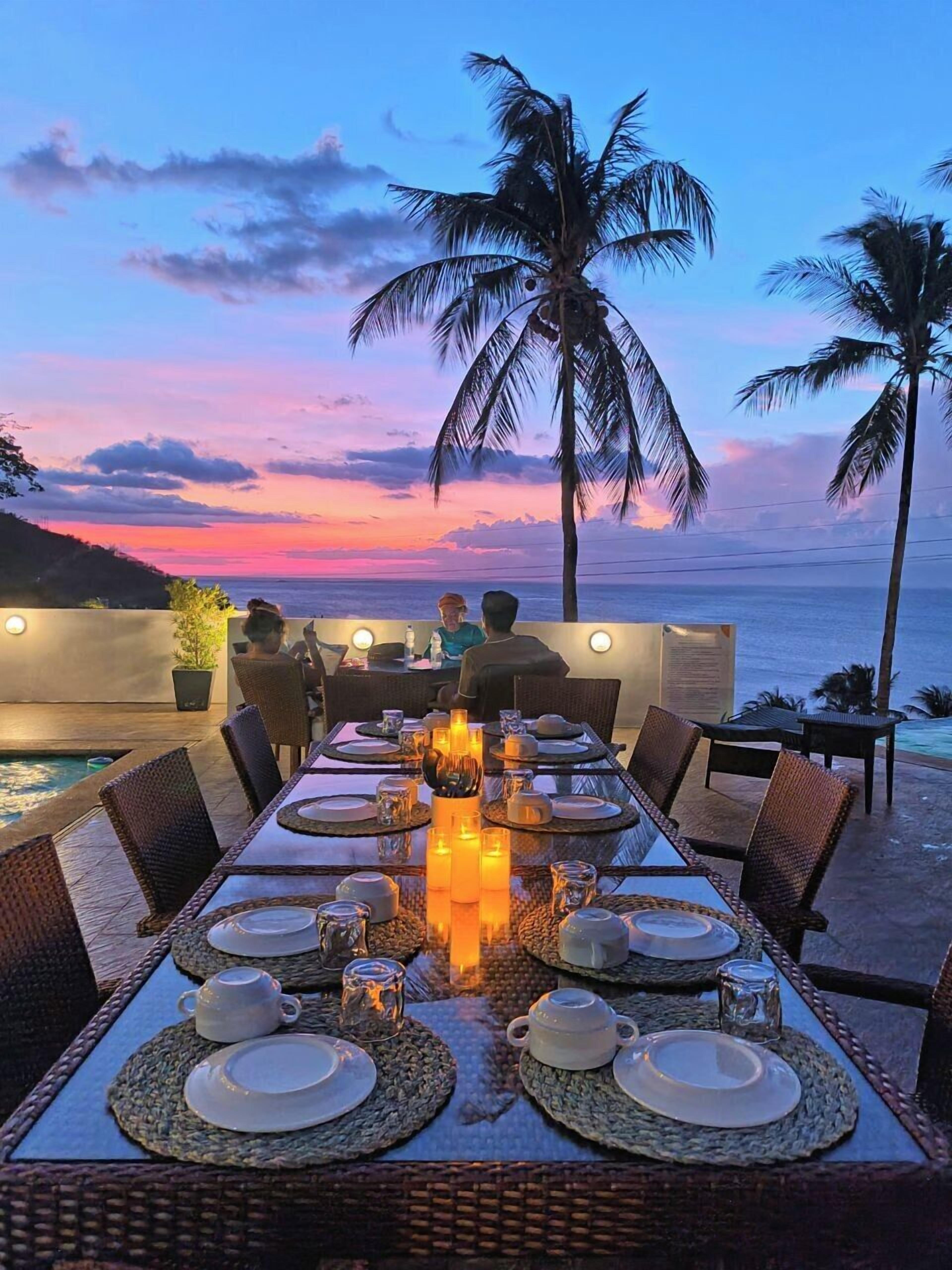 Vista do pôr do sol com uma mesa para dois, com vista para o oceano.