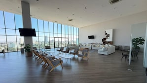 Uma sala de estar ampla e moderna, com grandes janelas, piso de madeira e móveis contemporâneos.