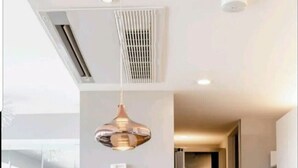 Uma cozinha moderna com bancada de granito, luminária pendente em cobre e uma tigela decorativa com frutas.