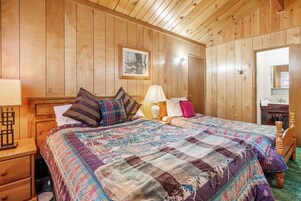 Quarto com painéis de madeira, uma cama grande, duas mesas de cabeceira e um espelho.