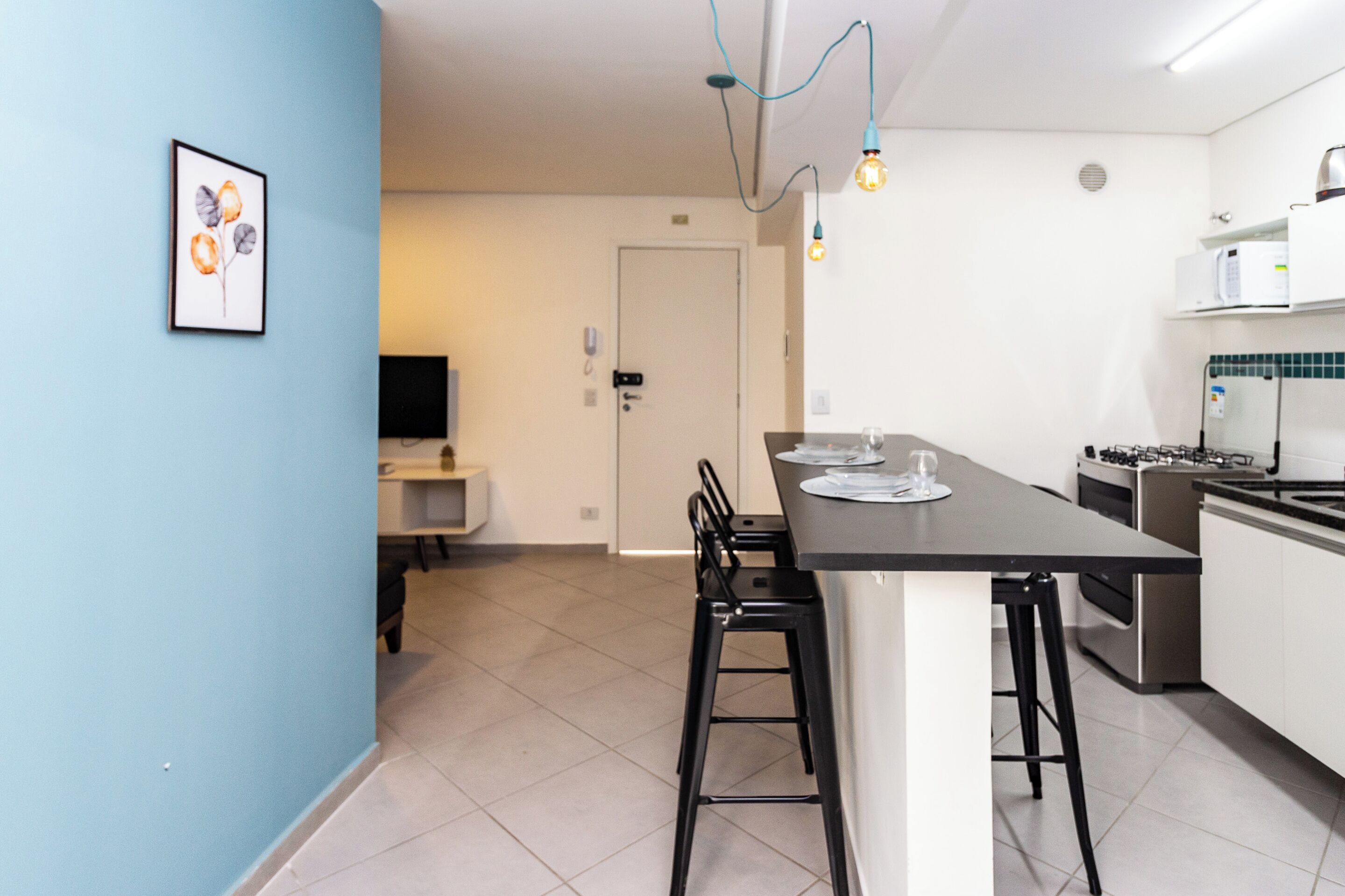 Uma cozinha moderna com uma ilha central, banquetas pretas e uma mesa de jantar.