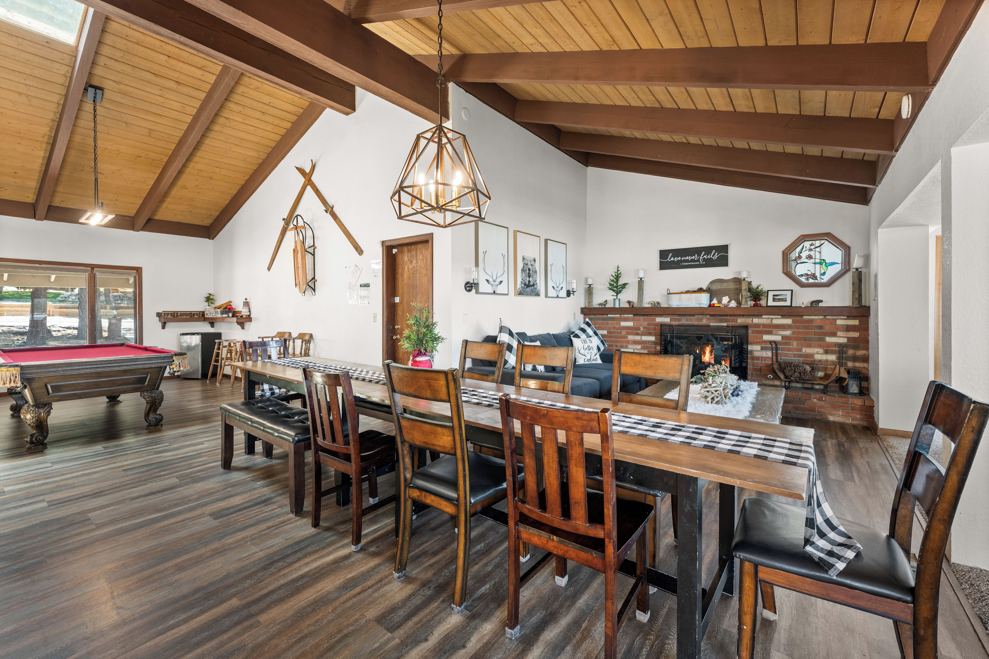 Uma ampla sala de jantar com mesa de bilhar, cadeiras de madeira e lareira de tijolos.
