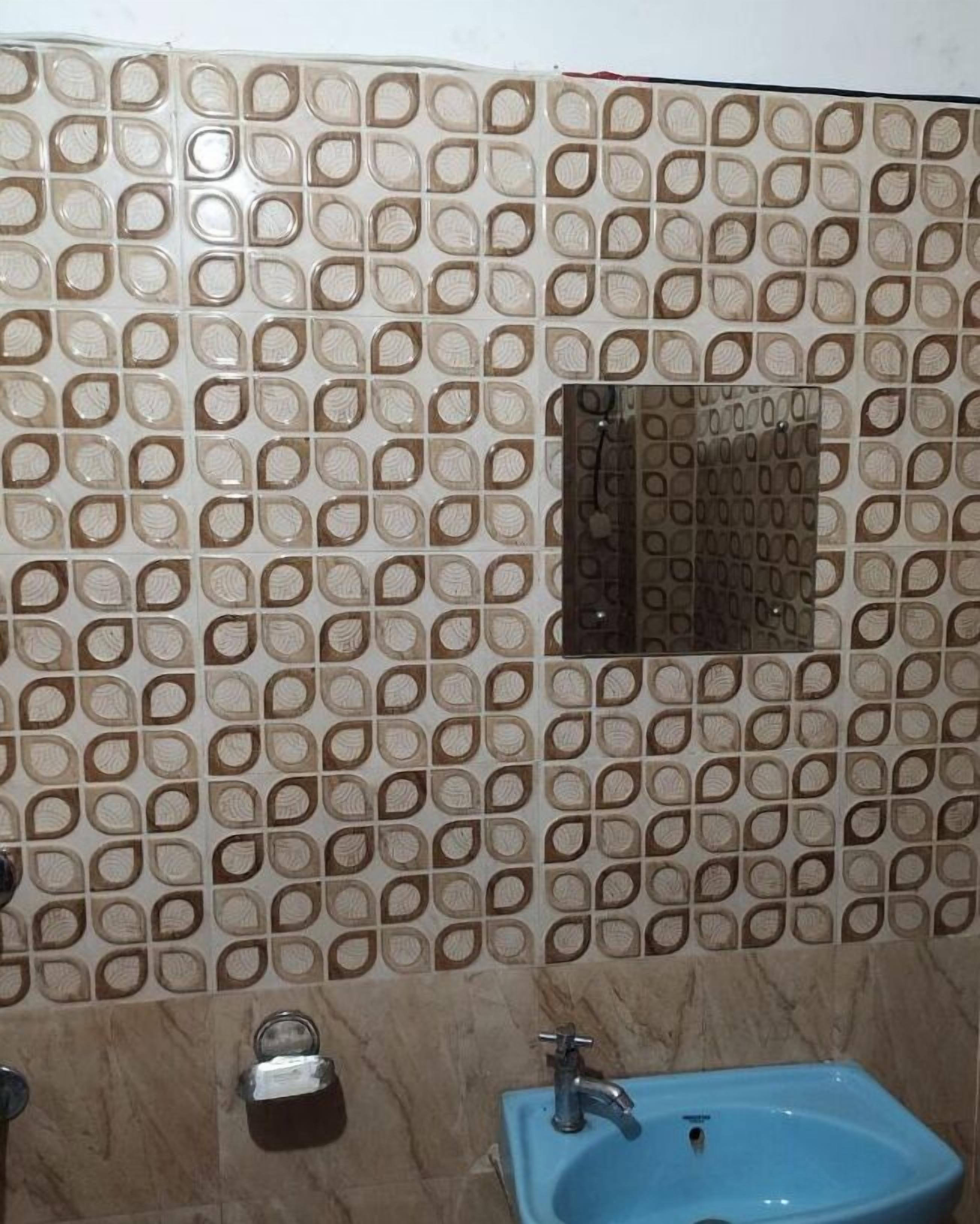 Uma casa de banho com uma pia azul, um espelho e um papel de parede estampado.