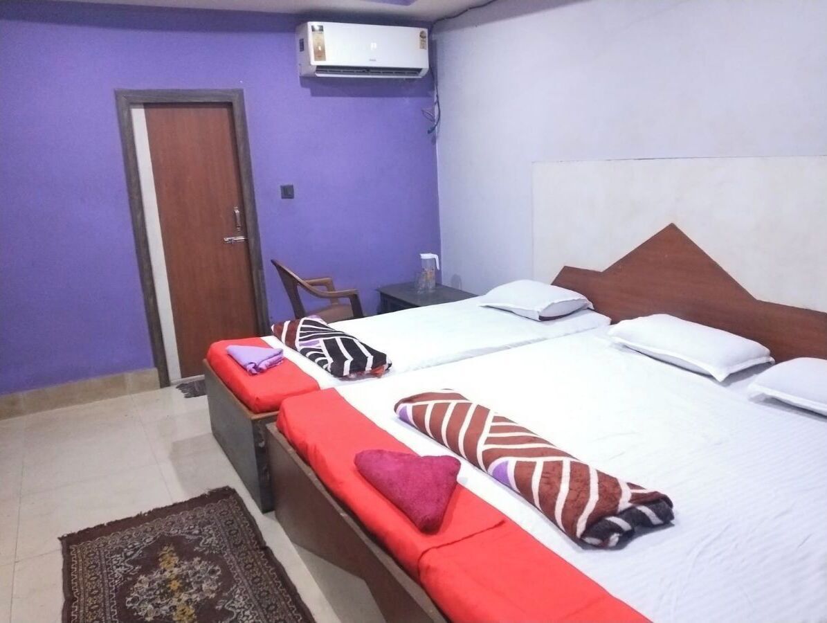 Quarto com cama, almofadas, mesa de cabeceira, cadeira e ar condicionado.