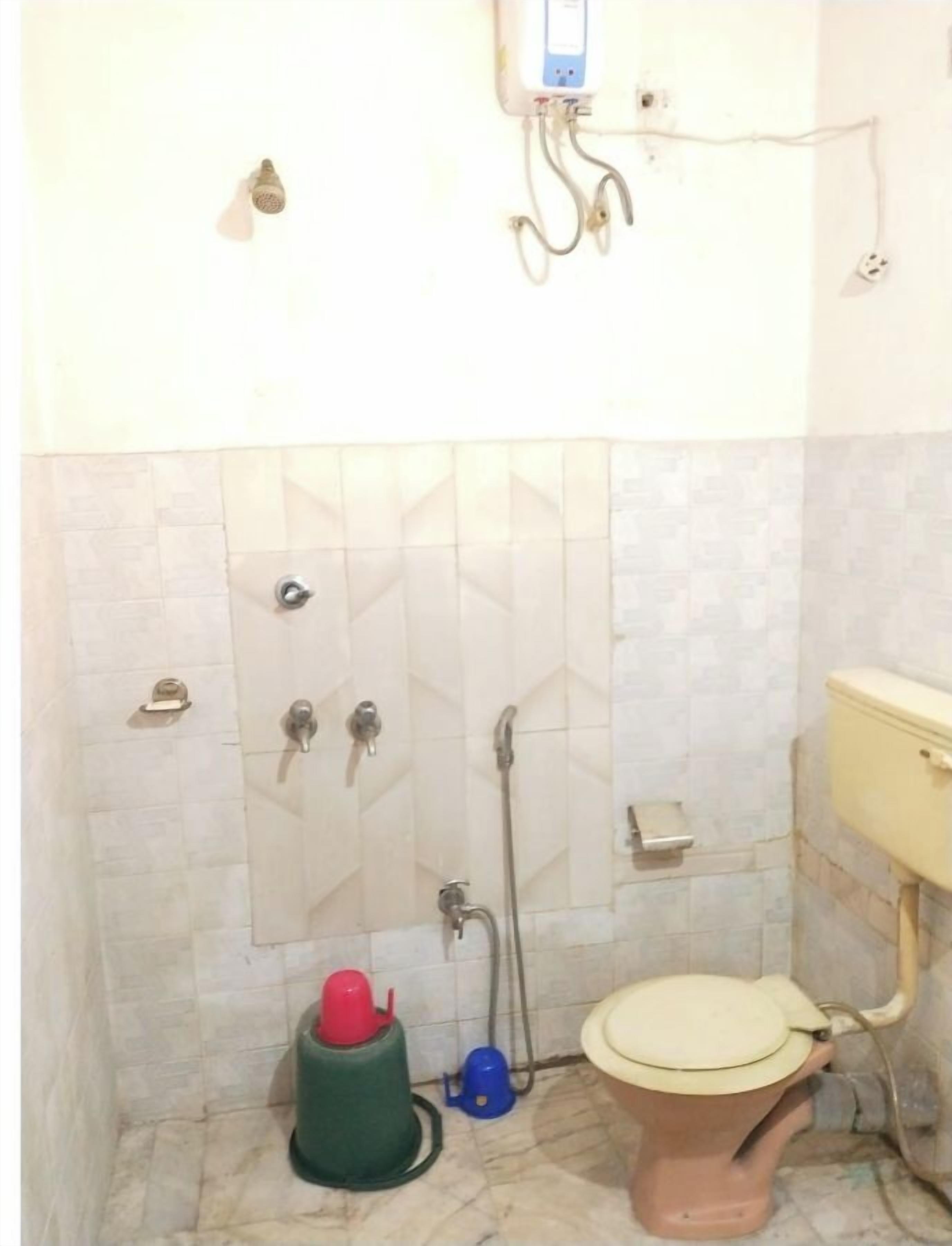 Casa de banho com sanita, chuveiro e lavatório.