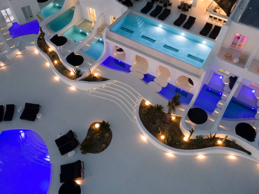 Uma área de piscina interior com vários níveis, diferentes opções de assento e iluminação variada.