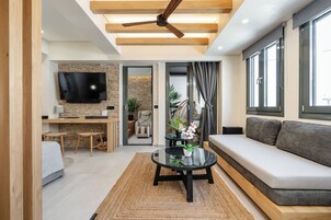 Uma sala de estar moderna com um sofá, uma mesa de centro, uma televisão e um espaço de jantar.