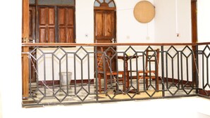 Um quarto com porta de madeira, um ornamento circular na parede e piso xadrez.