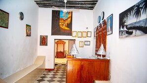 Um hall com piso xadrez, um balcão de recepção de madeira e diversas obras de arte nas paredes.