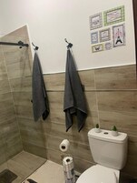 Casa de banho com duas toalhas penduradas numa barra, uma sanita e um rolo de papel higiénico.