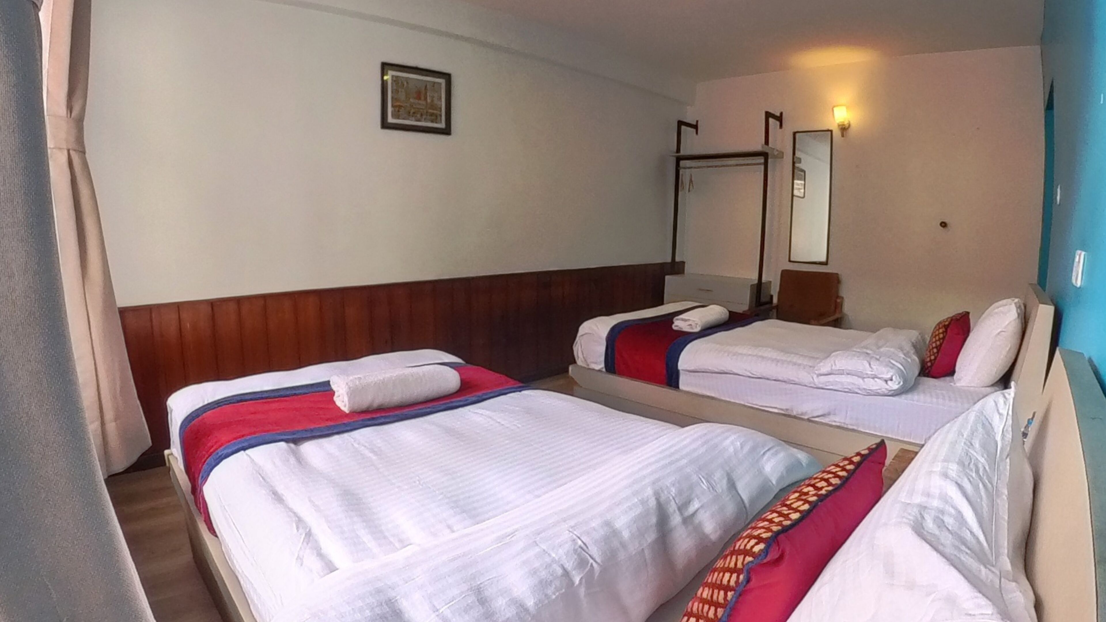 Quarto de hotel com duas camas, cabeceira de madeira, espelho e um quadro na parede.