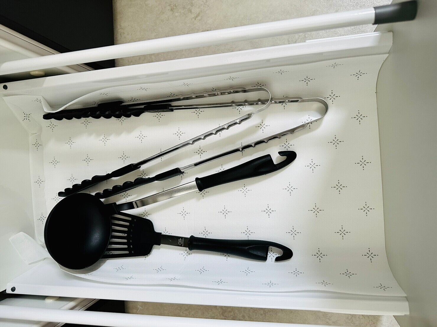 Uma gaveta de cozinha com utensílios, incluindo espátula, pinças e concha.