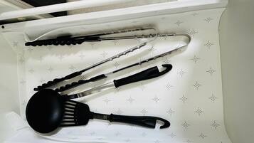 Uma gaveta de cozinha com utensílios, incluindo espátula, pinças e concha.