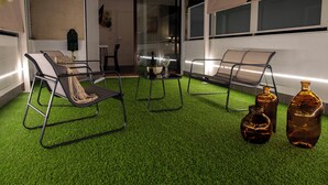 Um quarto com grama sintética verde, duas poltronas de descanso e duas garrafas grandes castanhas.