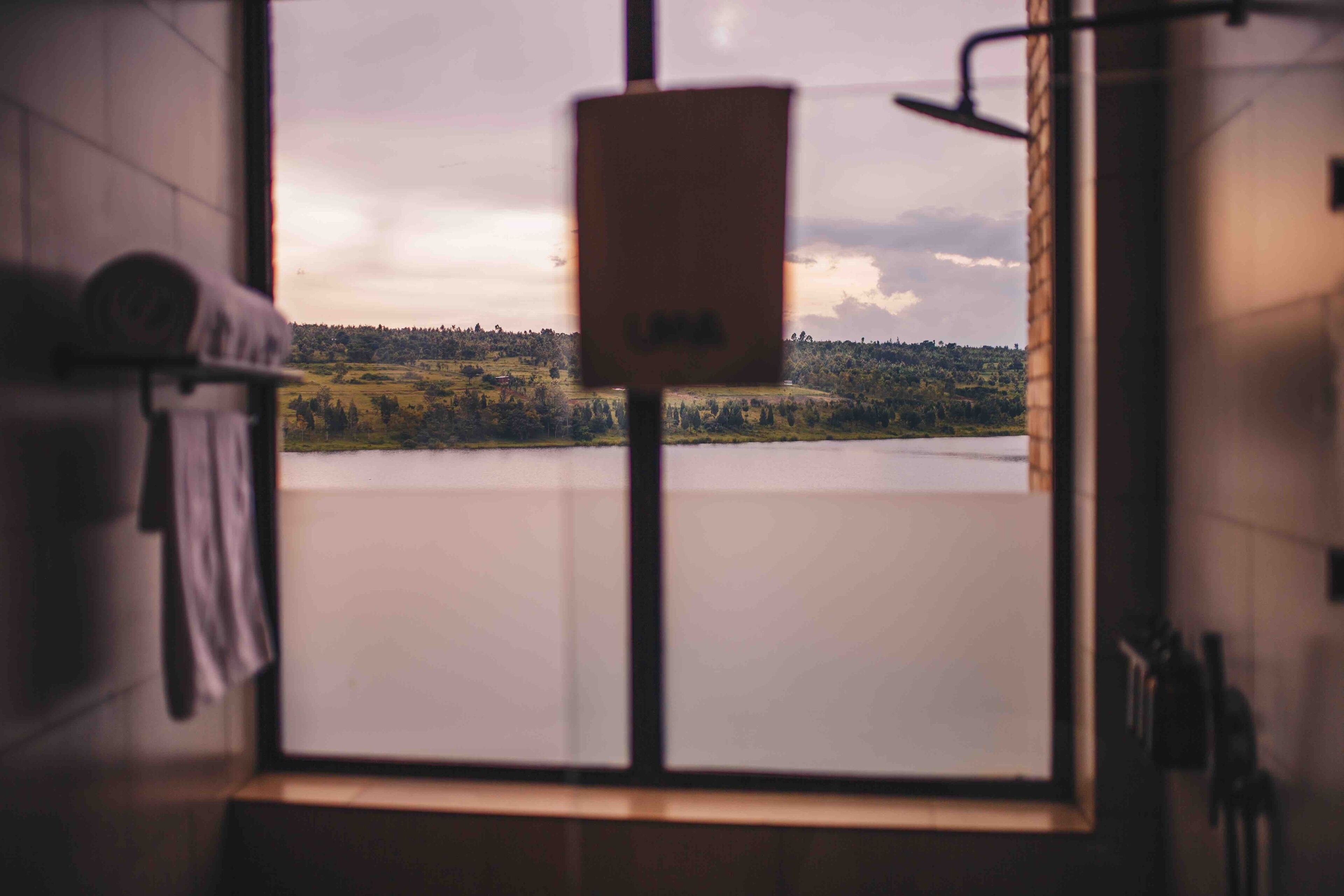 Casa de banho com vista para um lago e colinas.