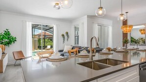 Cozinha moderna com ilha central, eletrodomésticos de aço inoxidável e iluminação pendente.