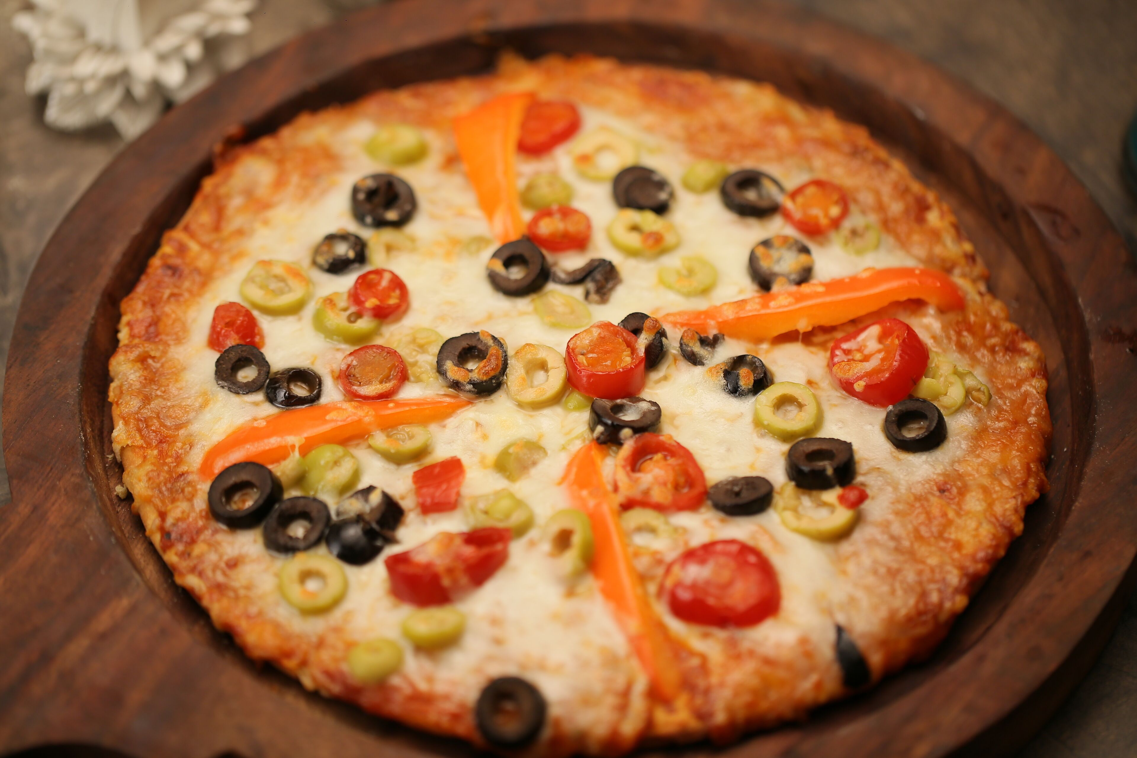 Uma pizza com diversos ingredientes sobre uma tábua de madeira.
