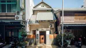 Uma casa japonesa tradicional com telhado de telhas, porta de madeira e plantas em vasos.