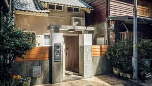 Uma casa japonesa tradicional com porta de madeira, pequeno alpendre e telhado de telhas.