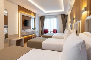 Quarto de hotel moderno com duas camas, uma TV, uma escrivaninha e uma cadeira.
