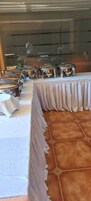 Uma mesa de banquete com diversas estações de serviço, toalha branca e piso estampado.