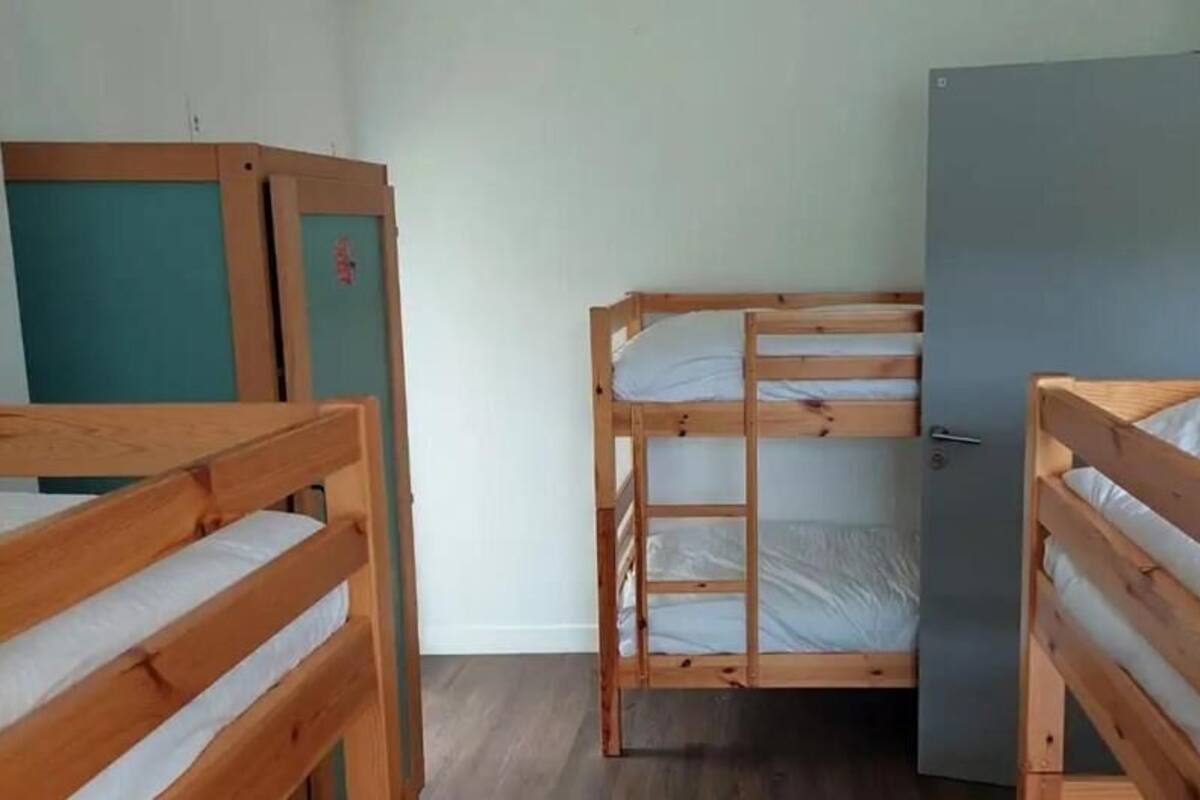 Quarto com três beliches, um guarda-roupa e uma porta.