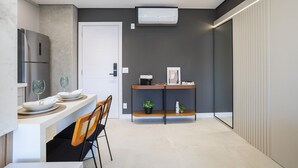 Uma cozinha moderna com geladeira embutida, uma mesa de jantar com cadeiras e um pequeno prateleira com objetos decorativos.