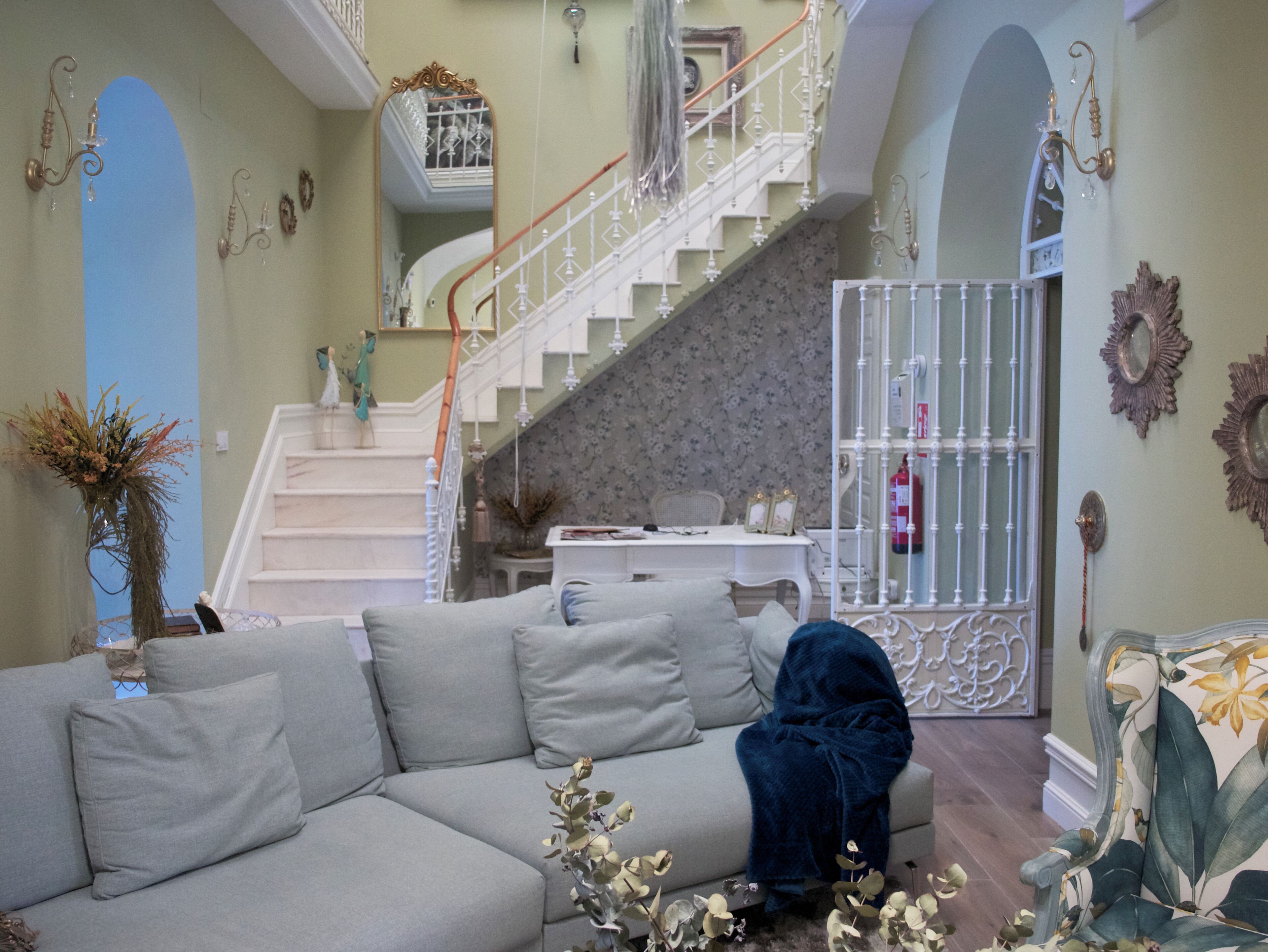 Uma sala de estar com sofá, escada e área de jantar.