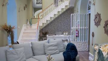 Uma sala de estar com sofá, escada e área de jantar.