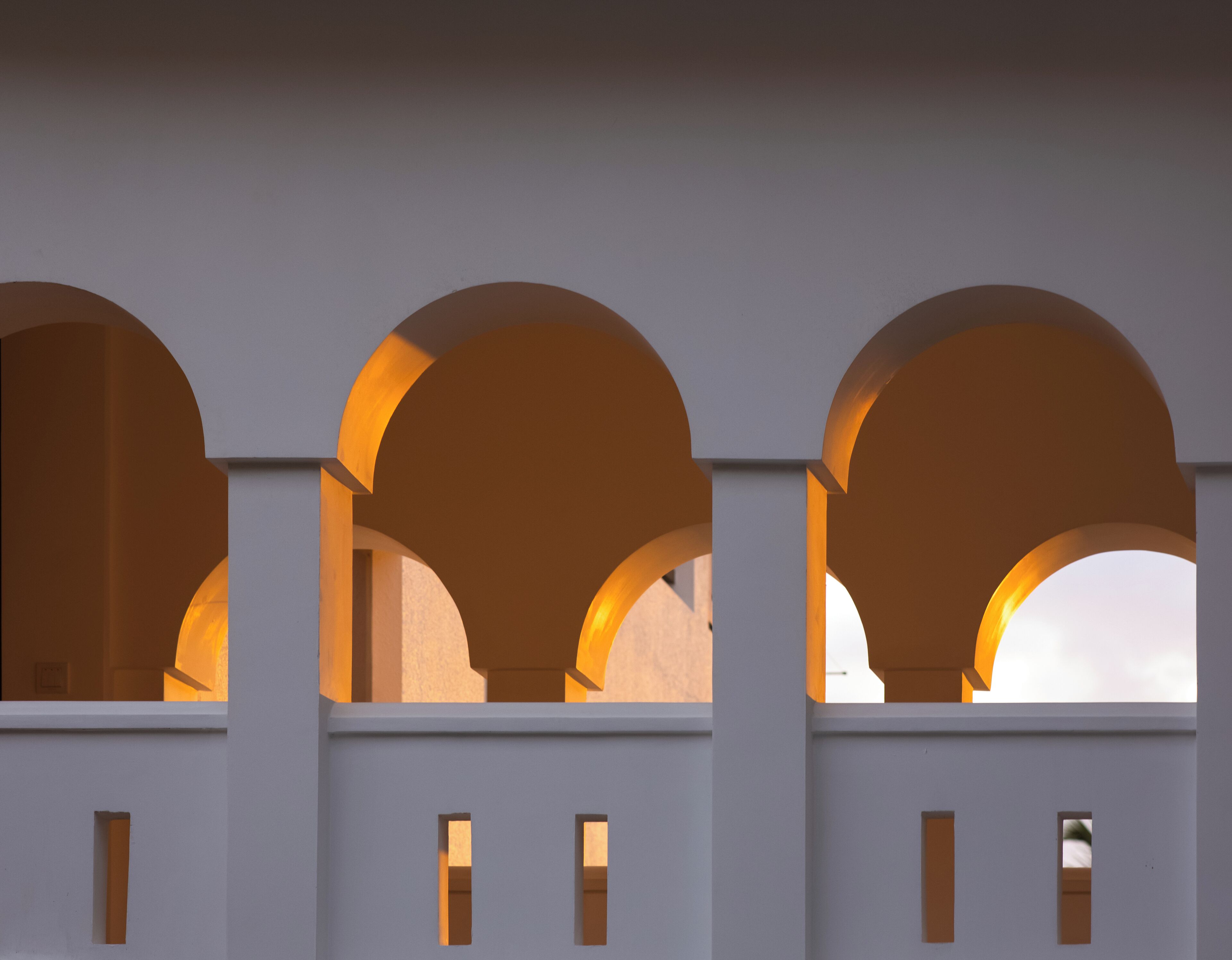Um edifício com três grandes aberturas em arco, cada uma delas com uma pequena janela abaixo.