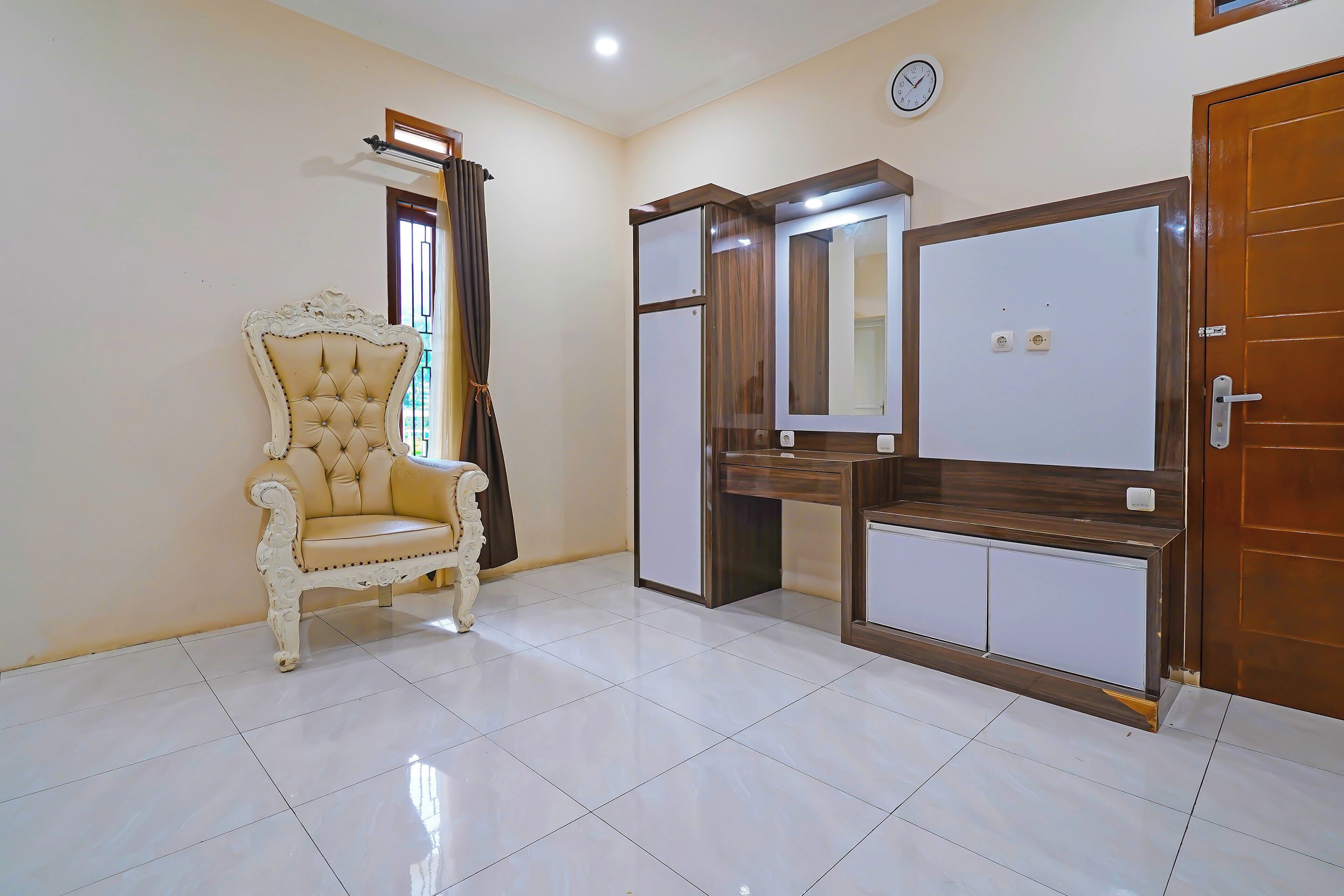 Quarto com um espelho grande, uma toucador com pia e uma poltrona confortável.