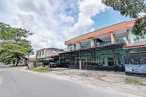 Um edifício com área externa coberta, estacionamento cercado e uma placa.