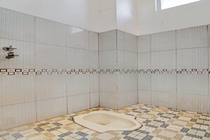 Casa de banho com sanita, paredes em azulejo e chão estampado.