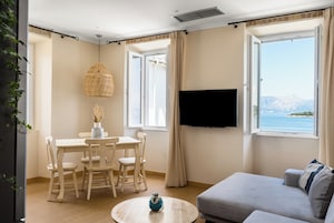 Uma sala de estar moderna com área de jantar, televisão de tela plana e uma grande janela com vista para as montanhas.