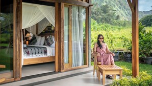 Uma cabana de madeira com uma cama e um espaço para sentar.