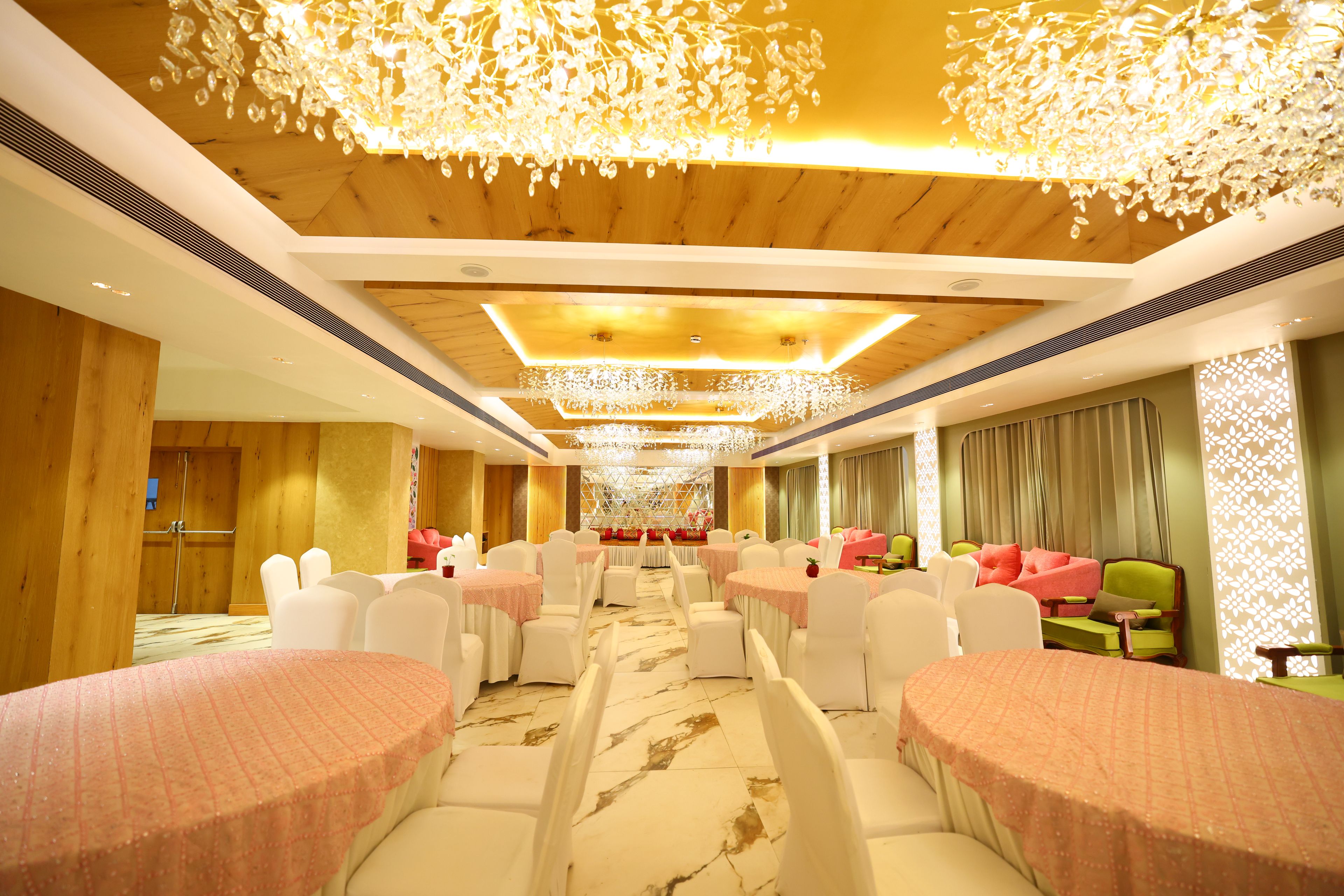 Uma sala de banquetes com mesas redondas, cadeiras brancas e teto decorado.