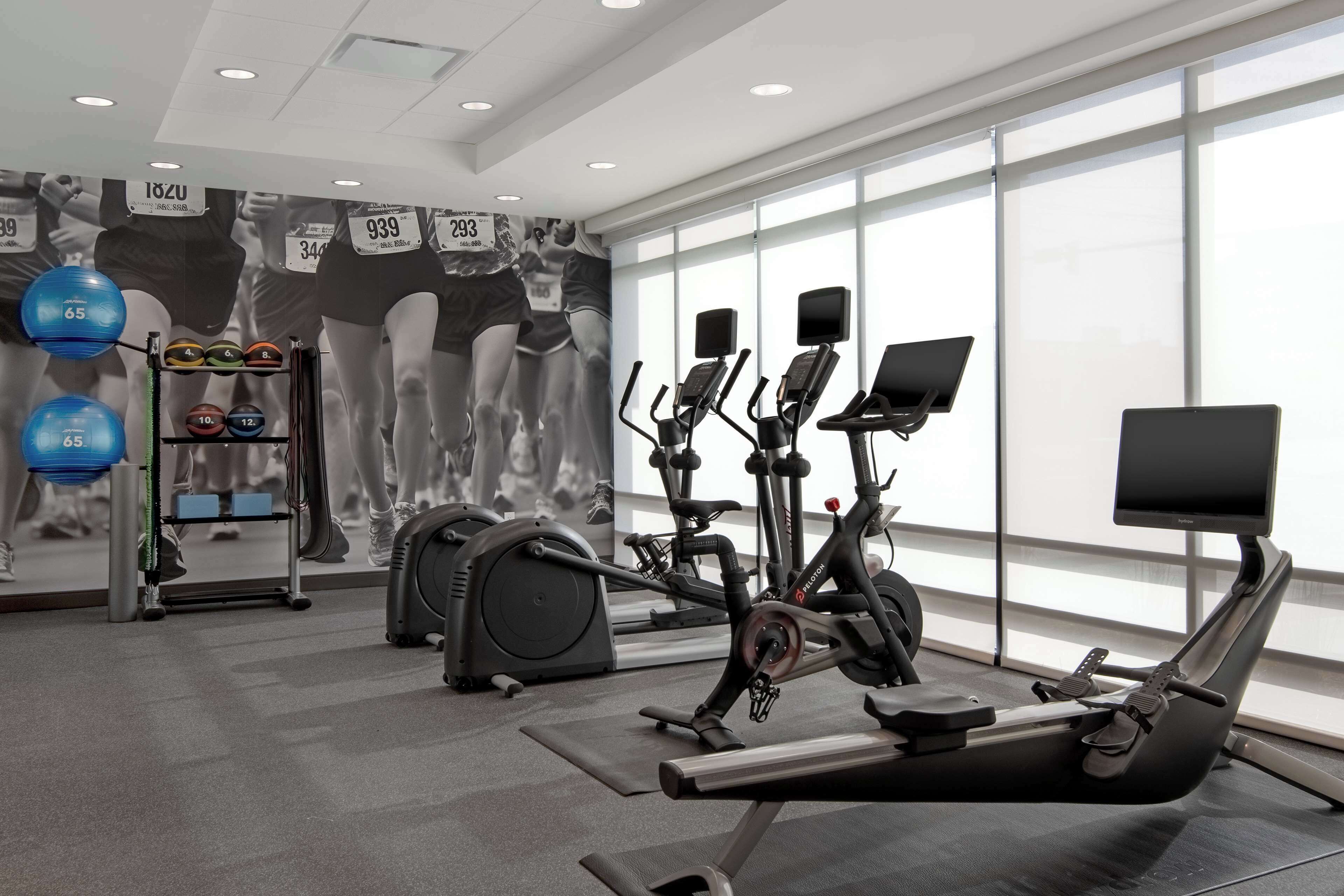 Uma academia moderna com máquinas de cardio, equipamentos de musculação e grandes janelas.