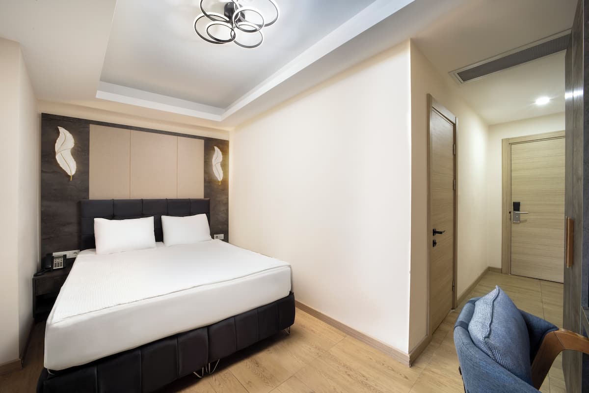 Quarto moderno com cama grande, mesa de cabeceira e uma cadeira.