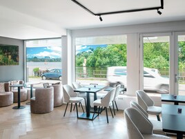 Decoração moderna com área de refeições, janelas amplas e vista para um rio e vegetação.