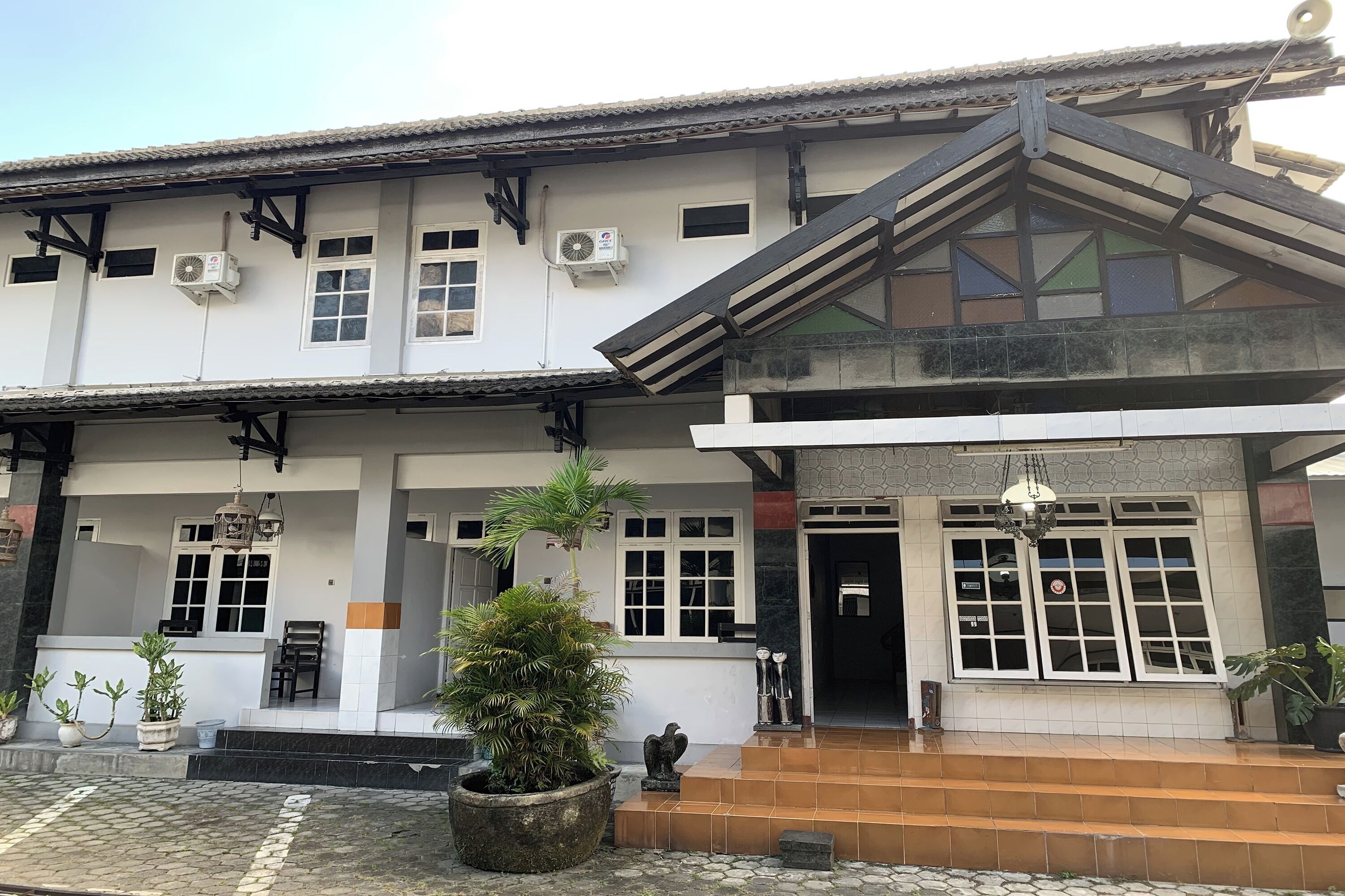 Um edifício de dois andares com telhado de telhas, várias janelas e uma escadaria que leva à entrada.
