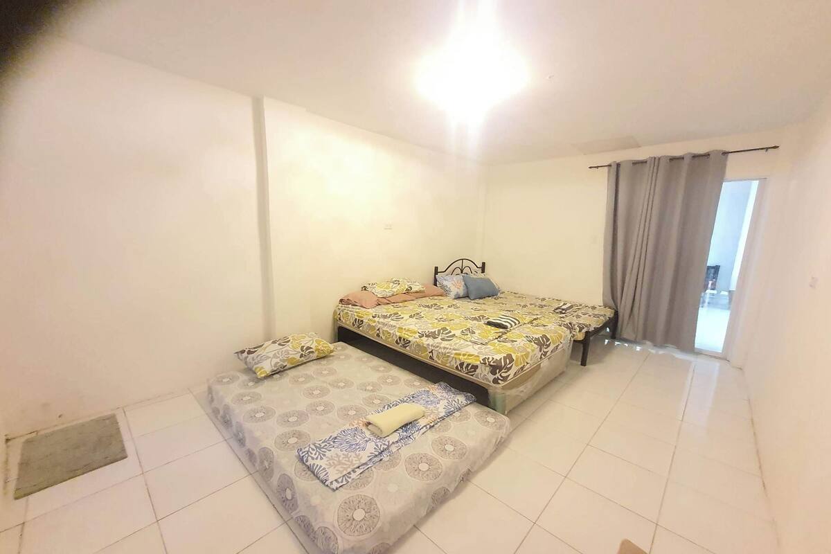 Quarto com duas camas, uma janela com cortinas e uma porta que dá para o exterior.
