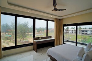 Quarto com uma cama grande, uma mesa e vista para os arredores.