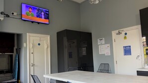 Uma cozinha moderna com uma ilha grande, uma televisão fixada na parede e diversos sinais de cozinha nos armários.