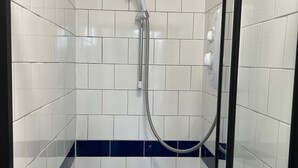 Box de chuveiro com azulejos brancos e uma faixa azul decorativa.