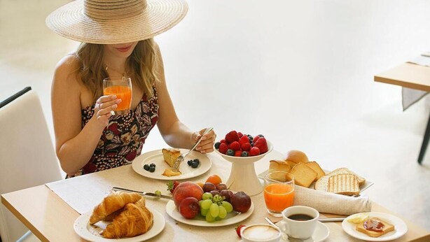 Mesa de café da manhã com croissants, frutas e suco.