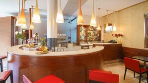 Uma área de bar com balcão curvo, cadeiras vermelhas e iluminação pendente.