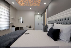 Quarto moderno com uma cama grande, cabeceira, mesa de cabeceira, espelho e guarda-roupa.