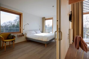 Um quarto com uma cama, uma cadeira, uma janela e uma porta.