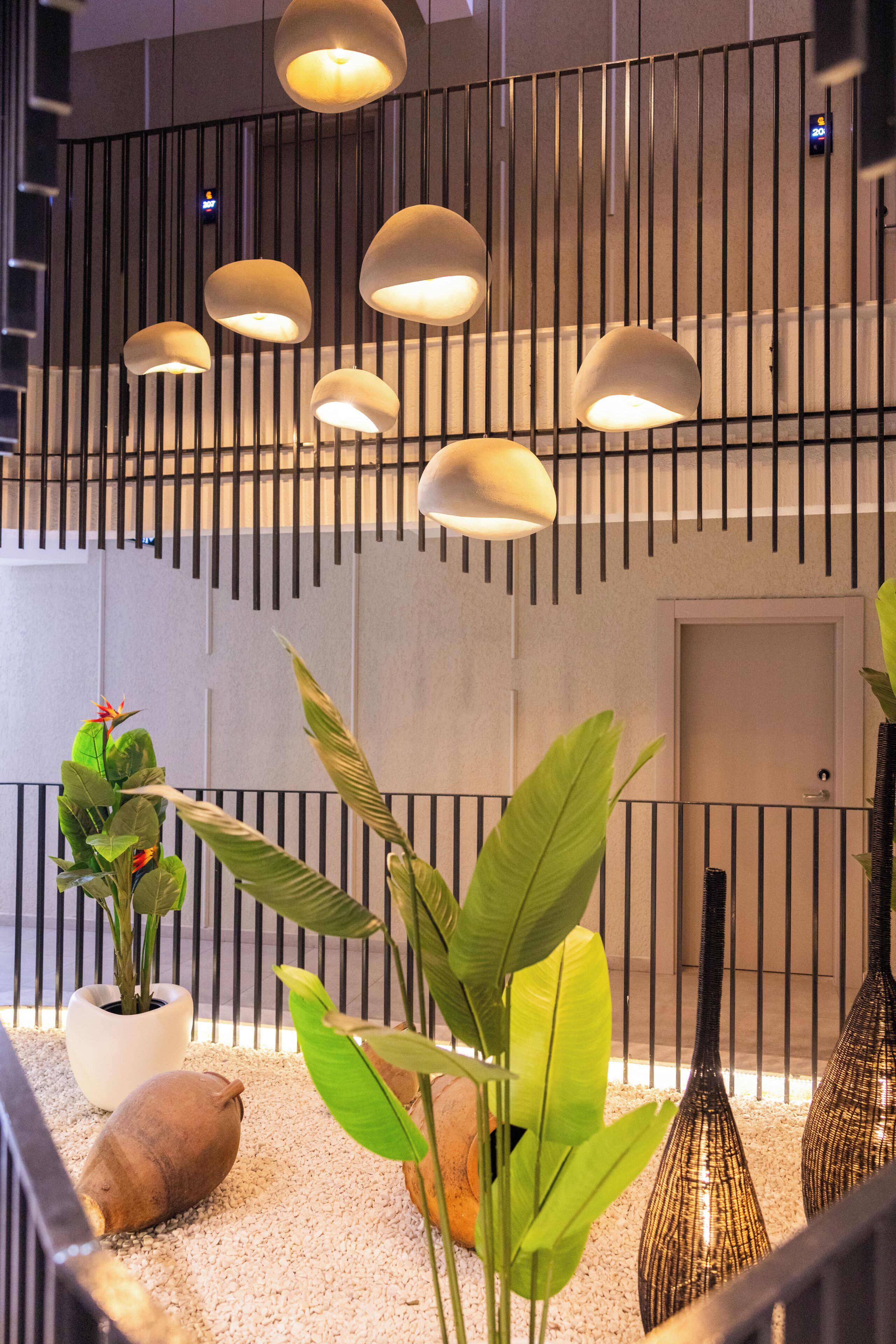 Um interior moderno com luminárias pendentes, um vaso com planta e parede com textura.