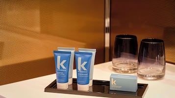 Uma bandeja com três produtos de cuidados corporais Kevin Murphy, dois copos e uma barra de sabão.
